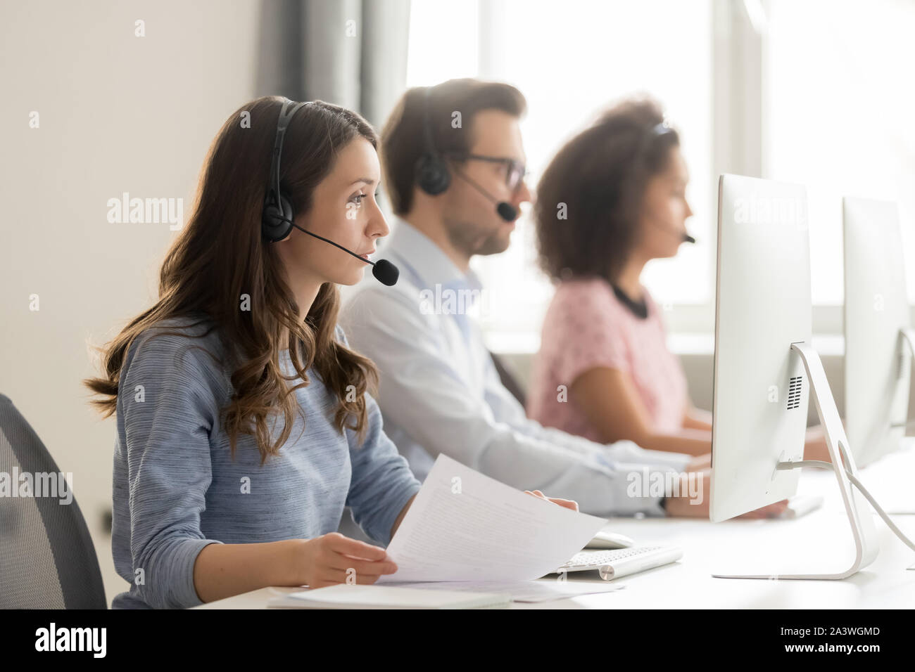 Call center worker holding paper talking with client use headset Stock ...