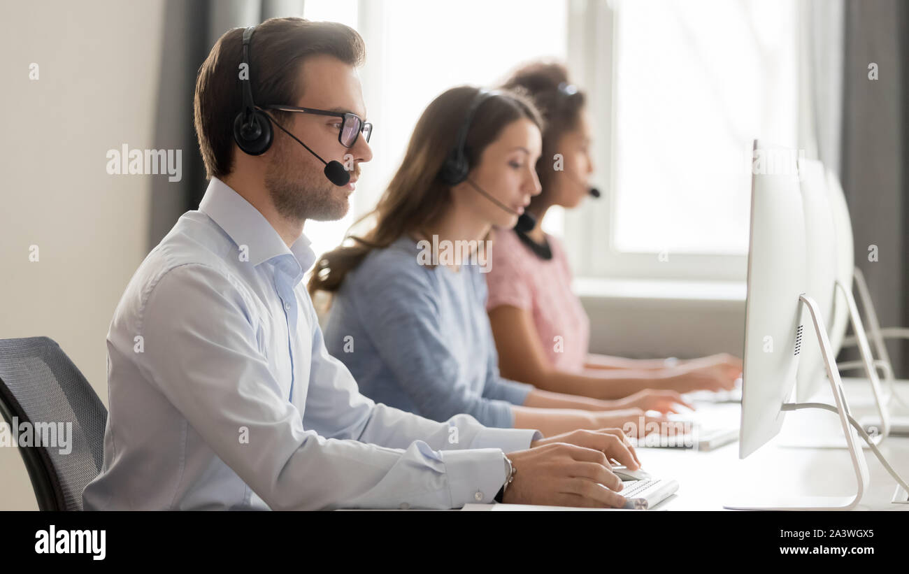 Side view call center employees working using computers and headsets ...