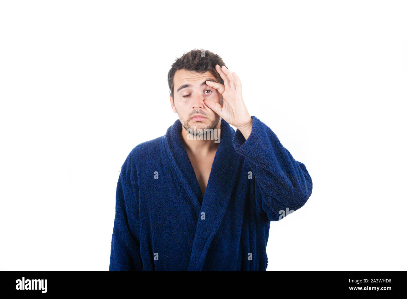 Portrait of sleepy young businessman wears blue bathrobe trying to hold ...