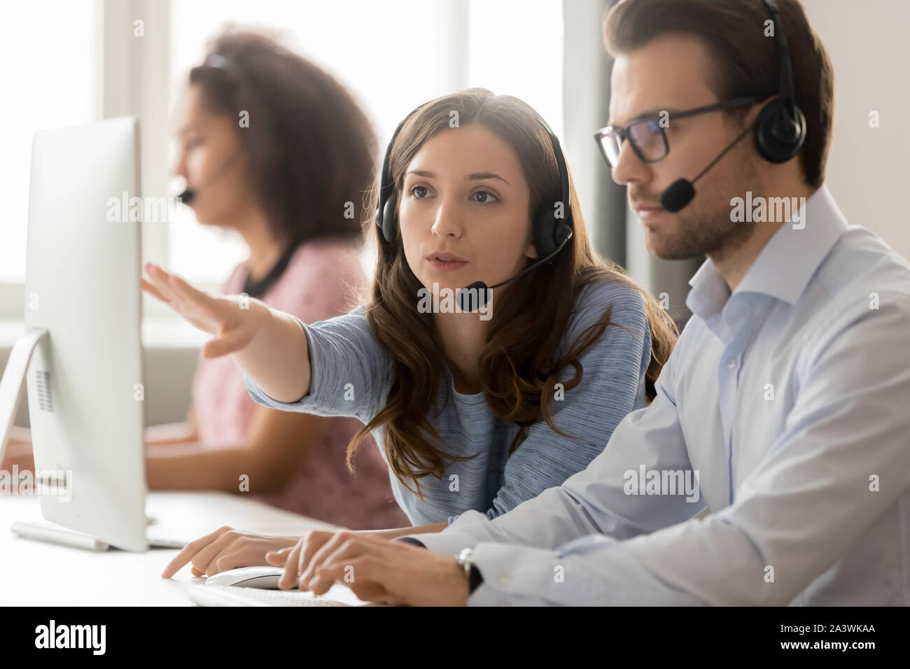 Call center female worker helping to man new employee colleague Stock ...