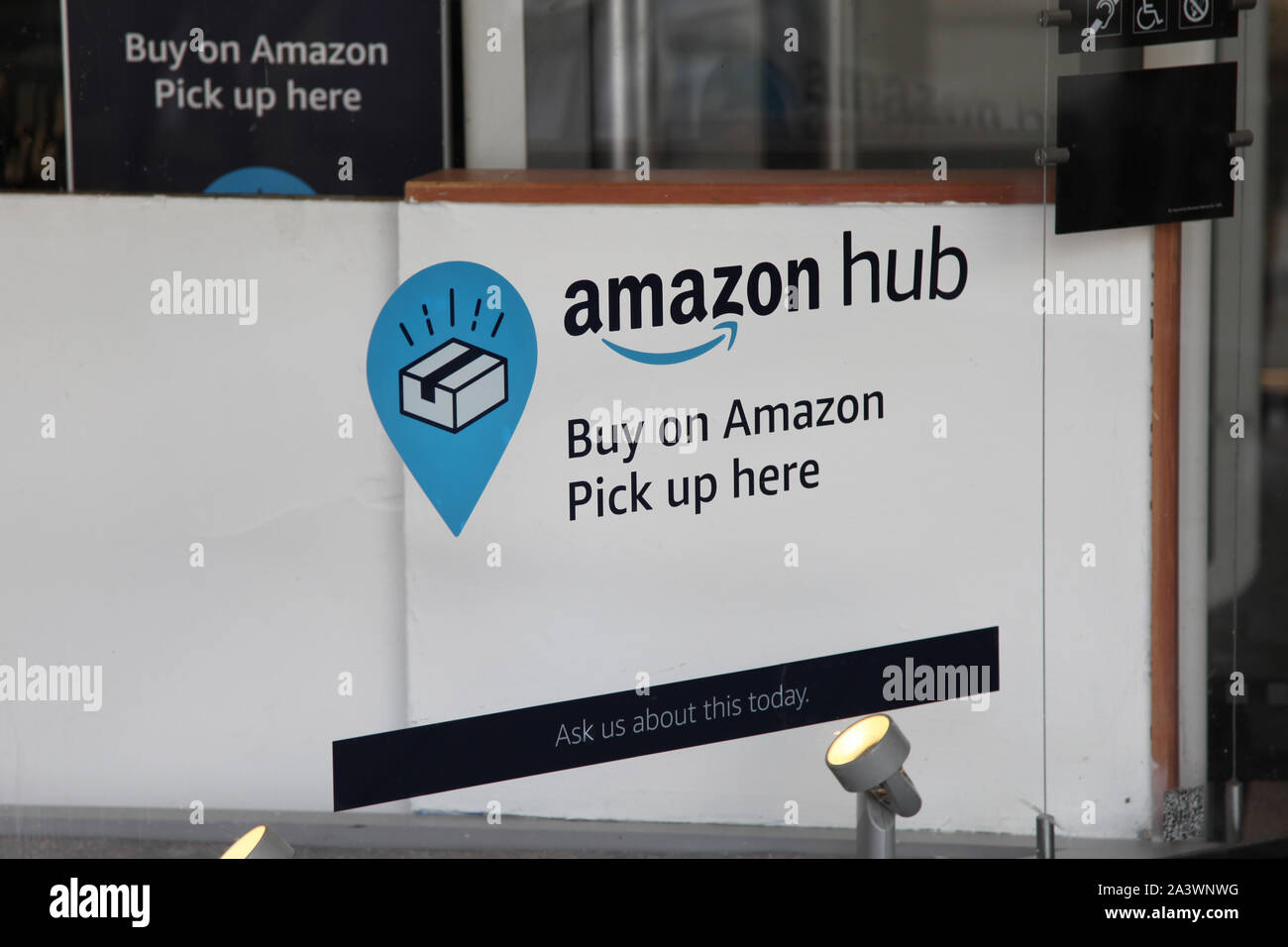 Amazon Hub pick up sign inside a shop window advertising where to pick ...
