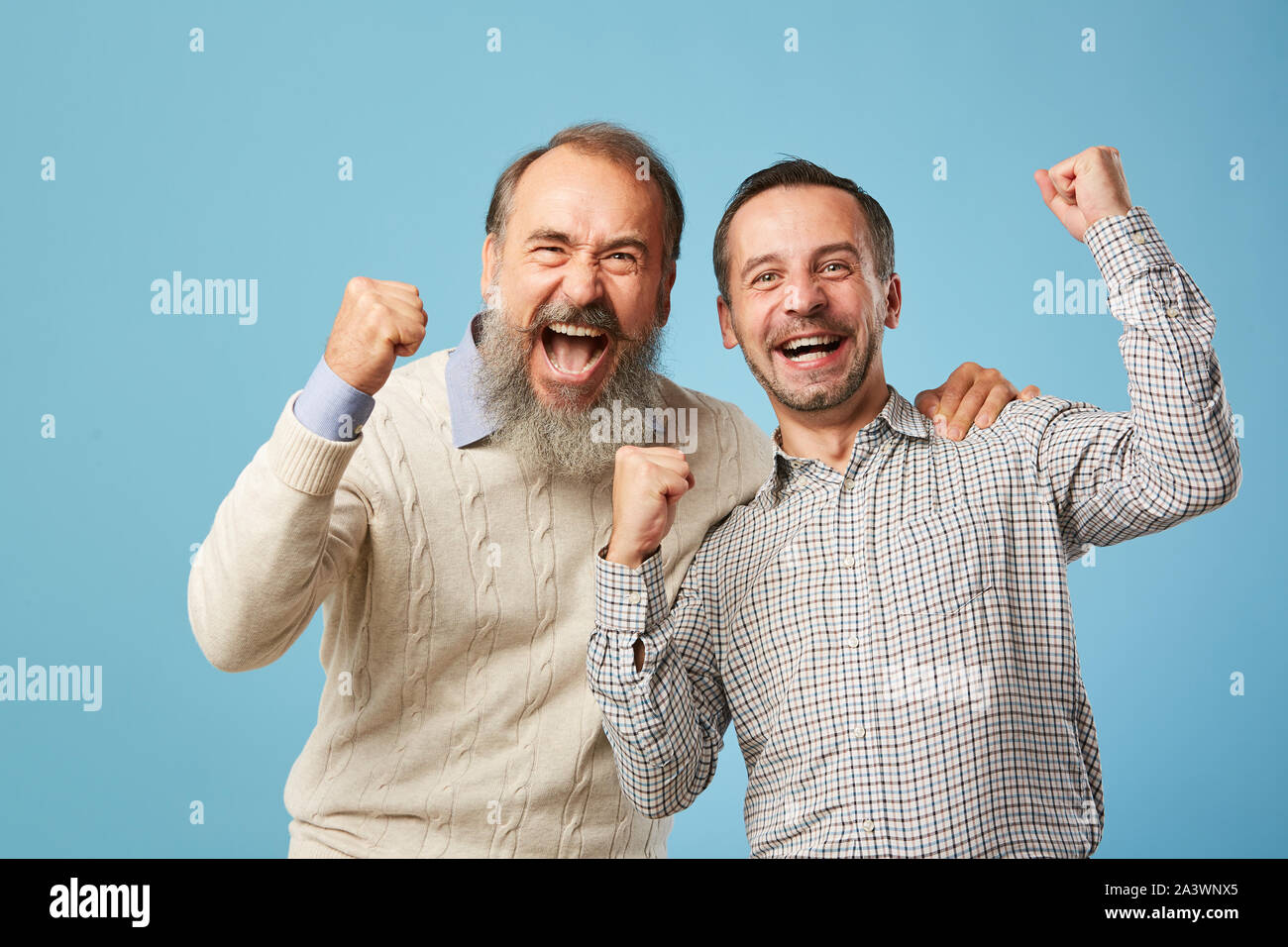 Portrait of two excited men standing together and looking very happy ...