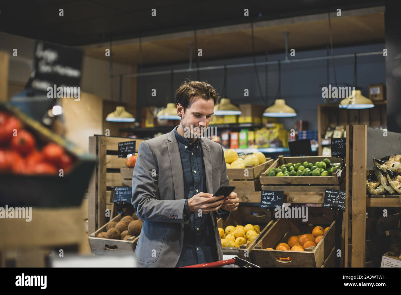 Adult male late night grocery shopping and using smartphone Stock Photo ...