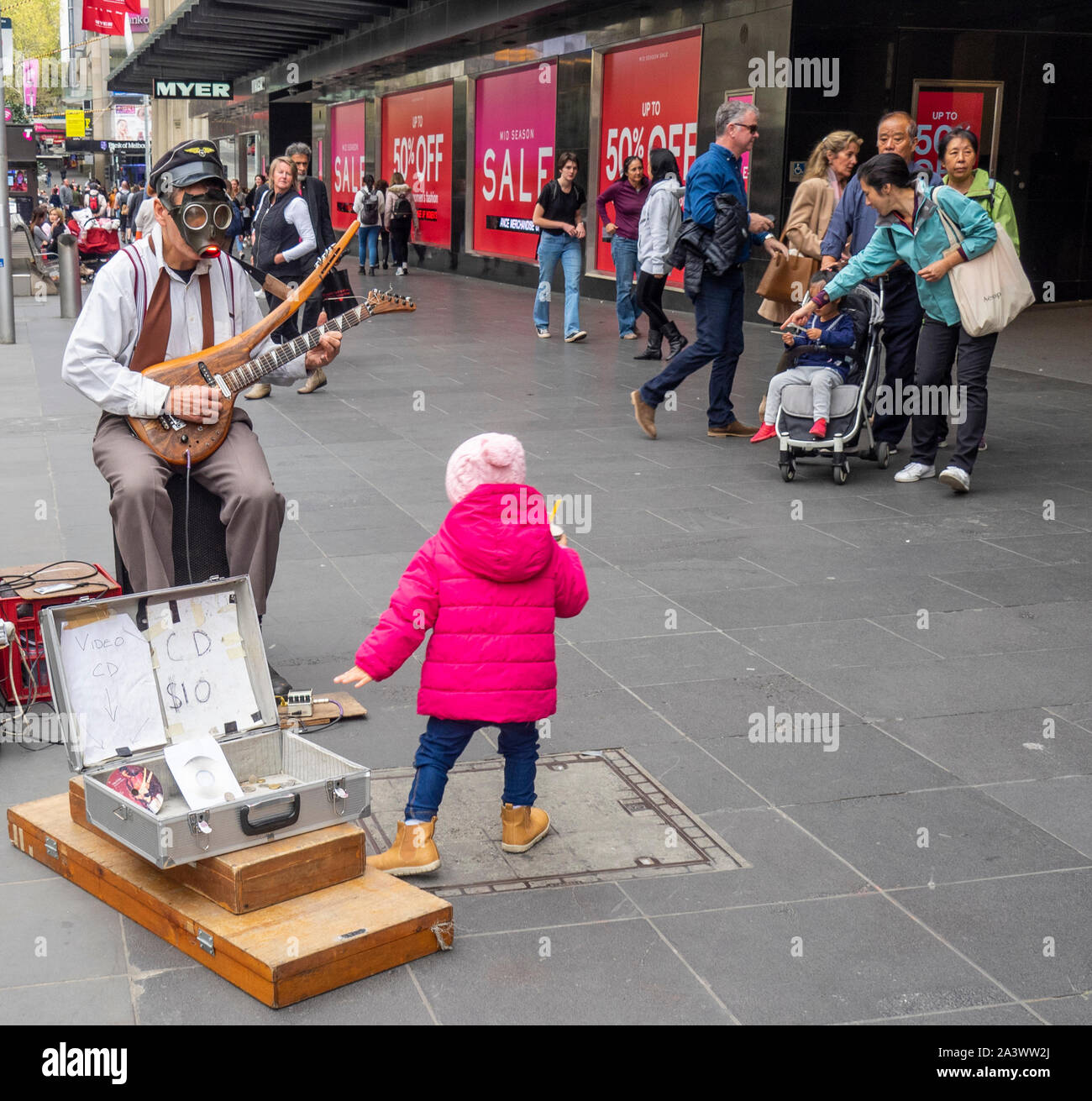 Male busker wearing a gas mask playing an electric guitar in Bourke St ...