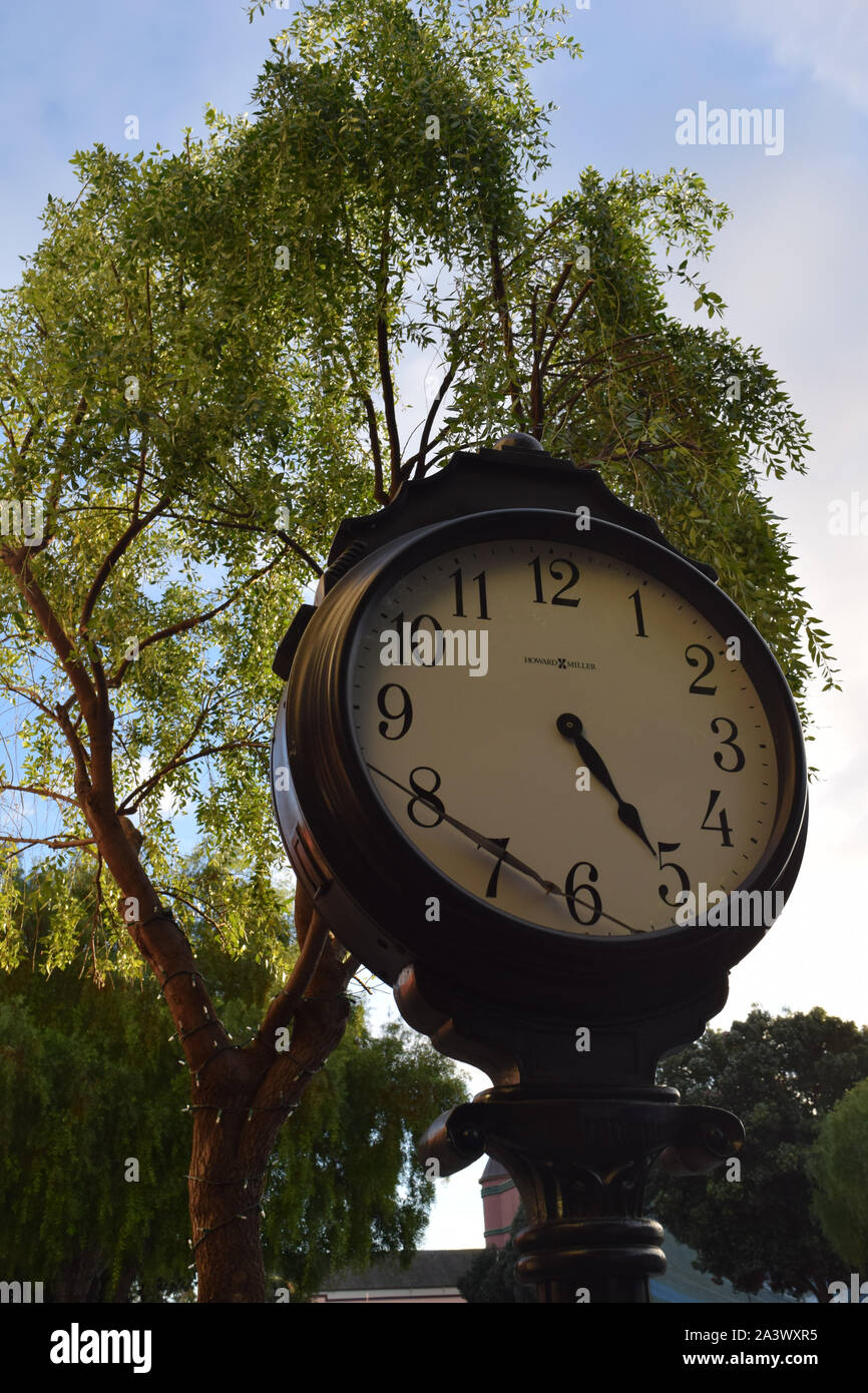 Broken clock on street with trees Stock Photo - Alamy