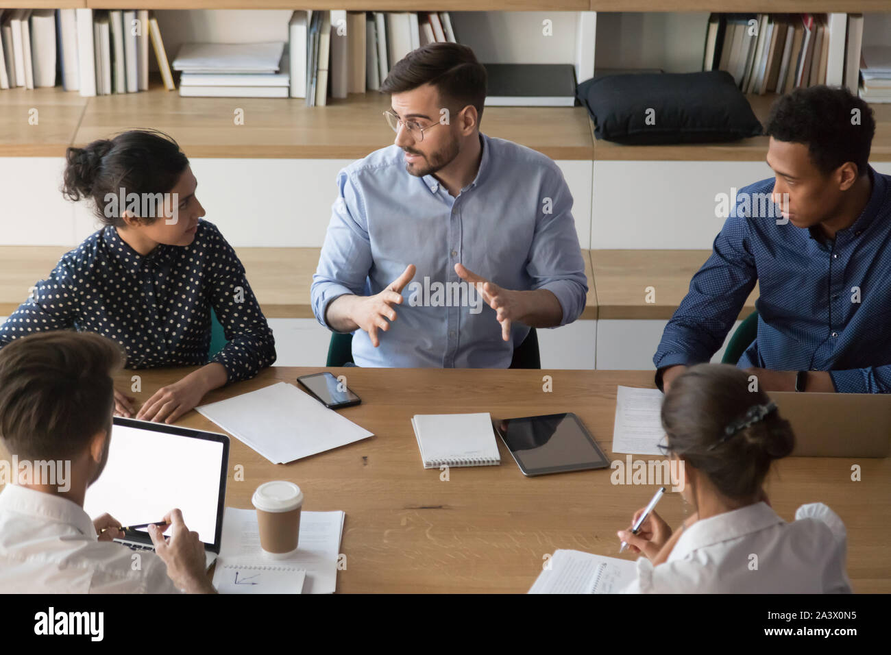 Skilled male manager talking to diverse business people at meeting ...