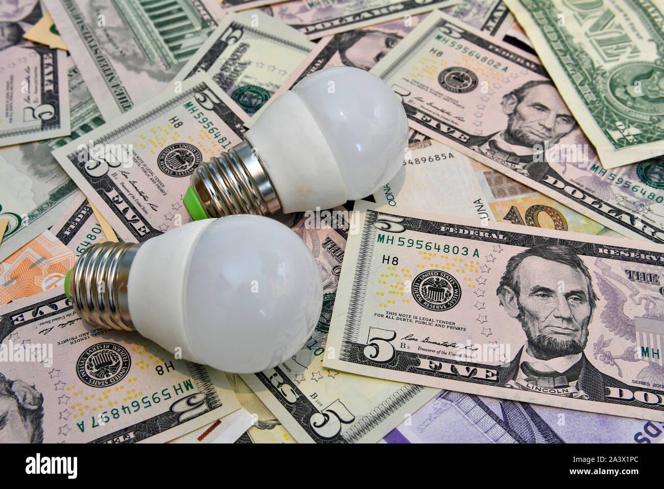 Two LED bulbs in the background of different countries currency notes ...