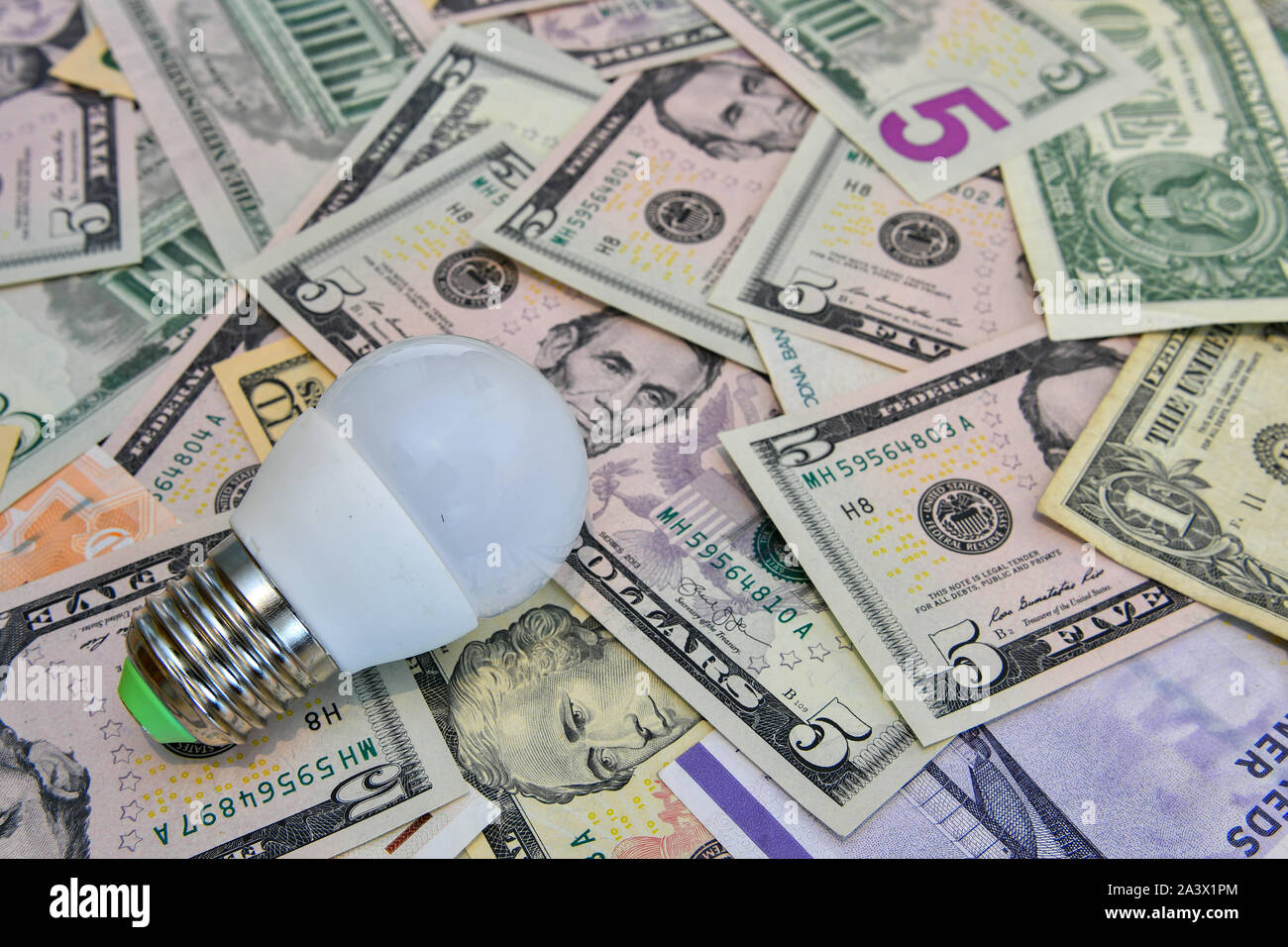 LED bulb in the background of different countries currency notes ...