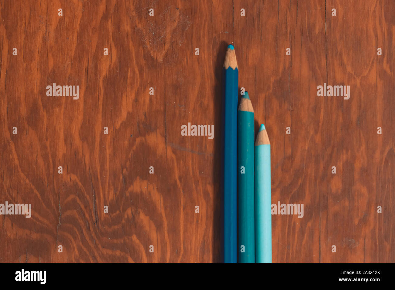 three colored pencils on wooden desk in isolated background to fill ...