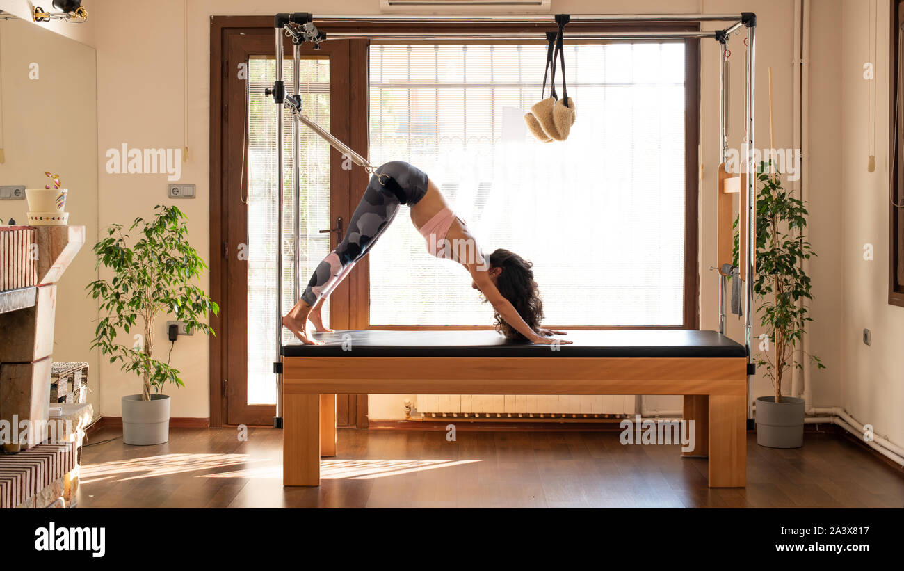 Pilates Woman stretching on pilates cadillac. Young female pilates ...