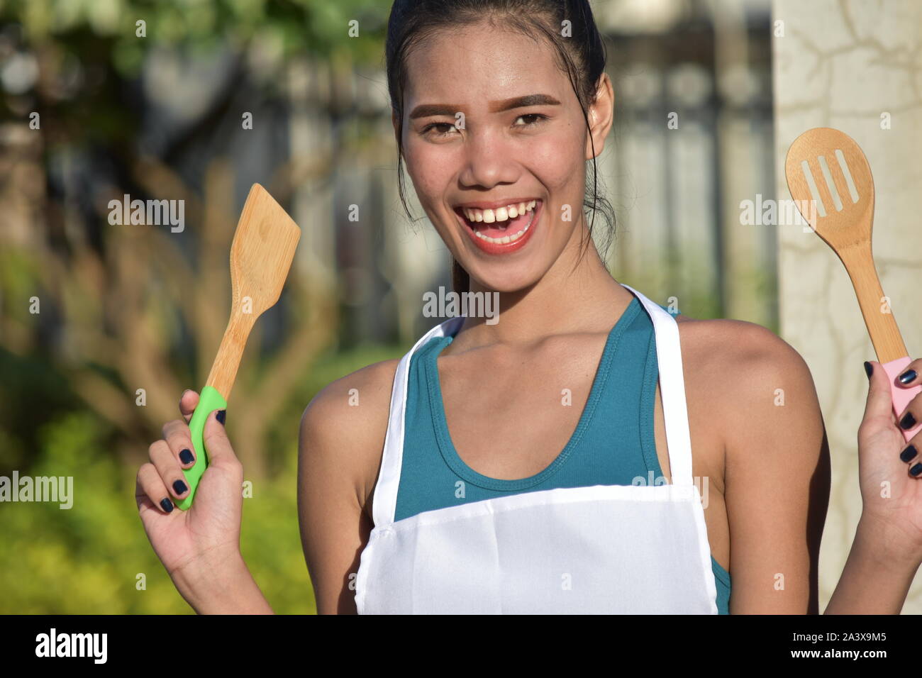 Asian Female Cook Laughing Wearing Apron With Utensils Stock Photo - Alamy