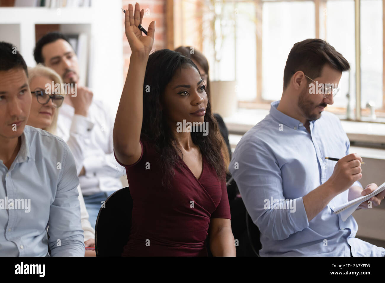 Motivated black female raise hand take part in training Stock Photo - Alamy