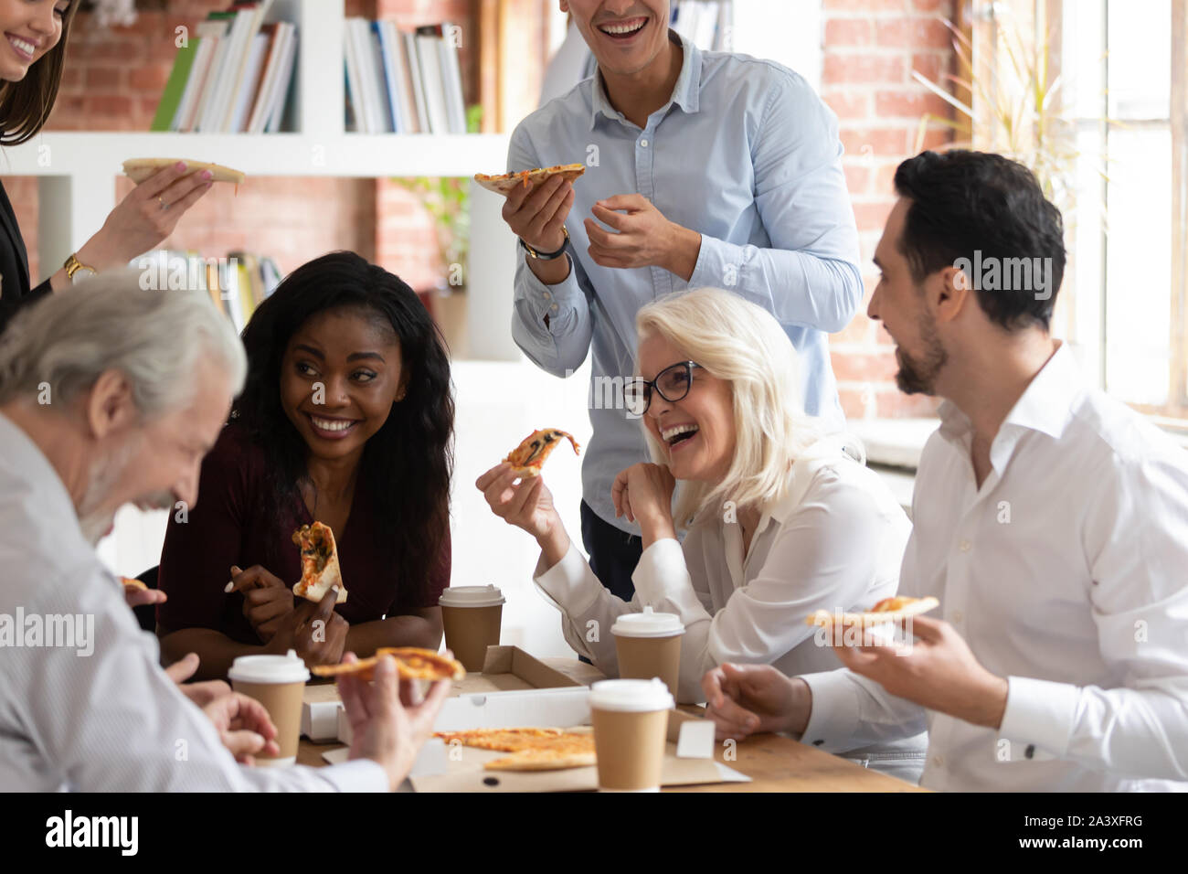 Happy diverse colleagues have lunch eating pizza together Stock Photo ...