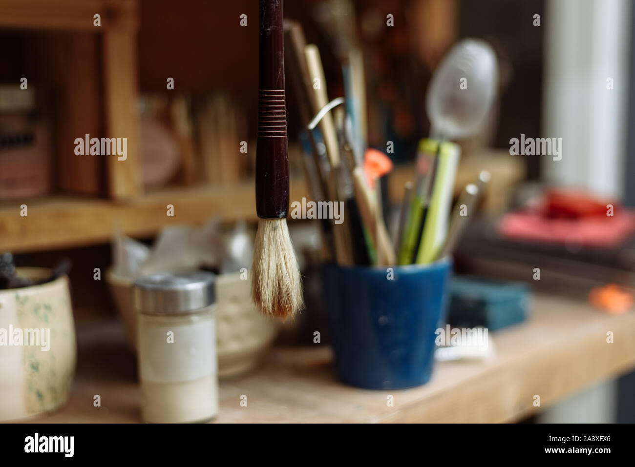 Art brushes in a potter's workshop. An old brush hangs from a shelf ...