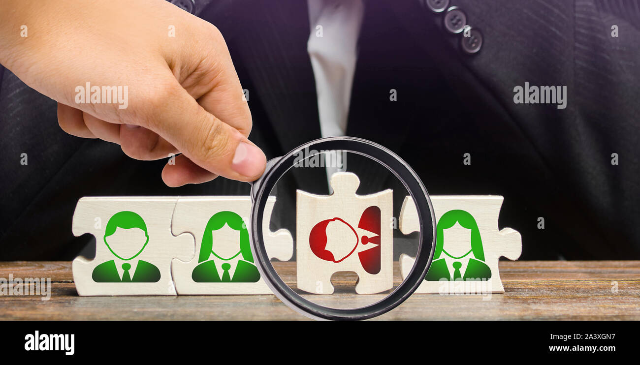 A magnifying glass looks at a businessman sitting in despair over the ...