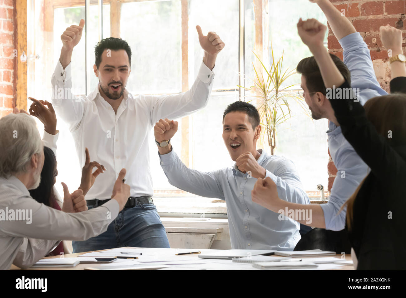 Excited diverse colleagues celebrate team win in office Stock Photo - Alamy