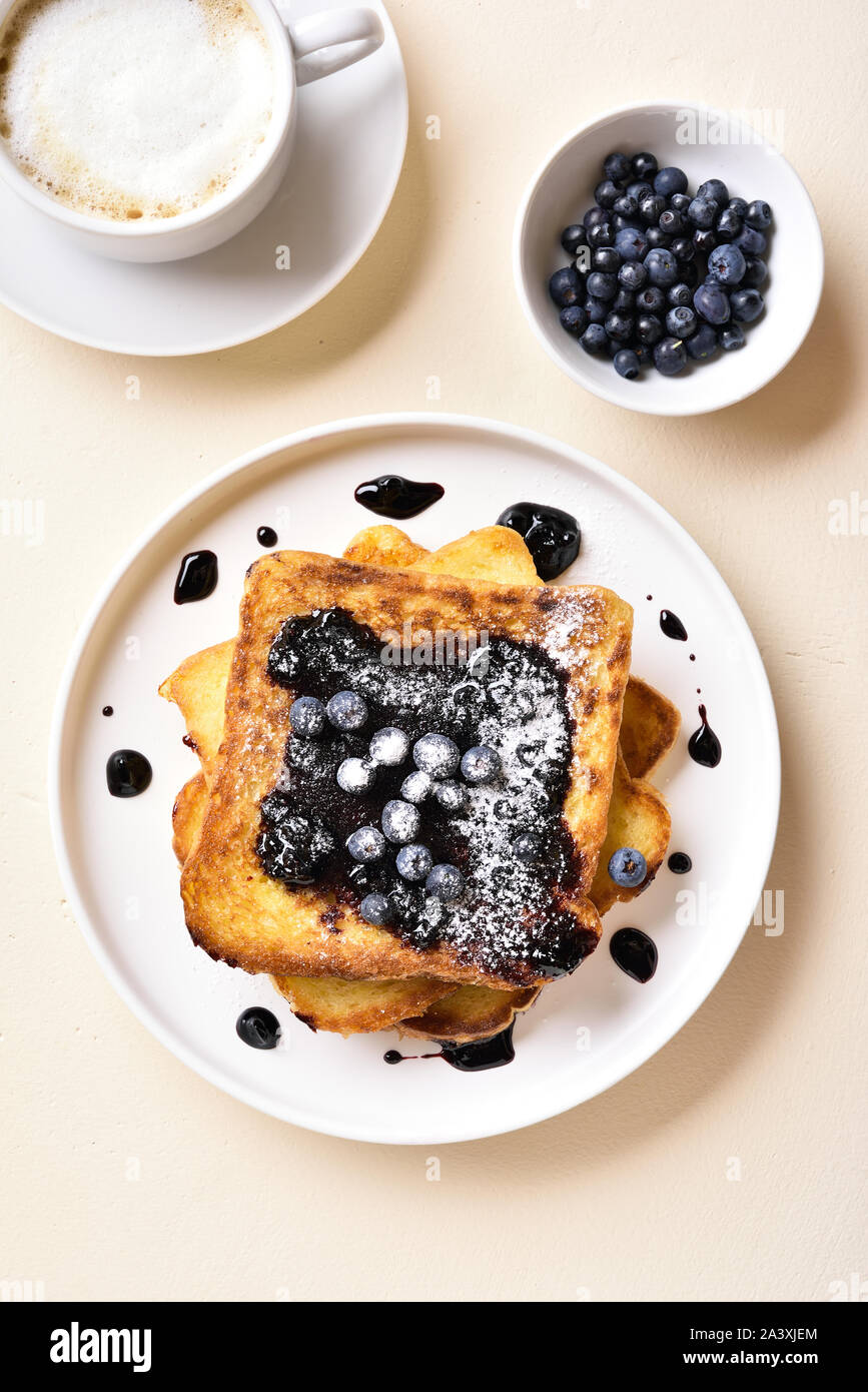 French toasts with blueberry sauce and cup of coffee on stone table ...