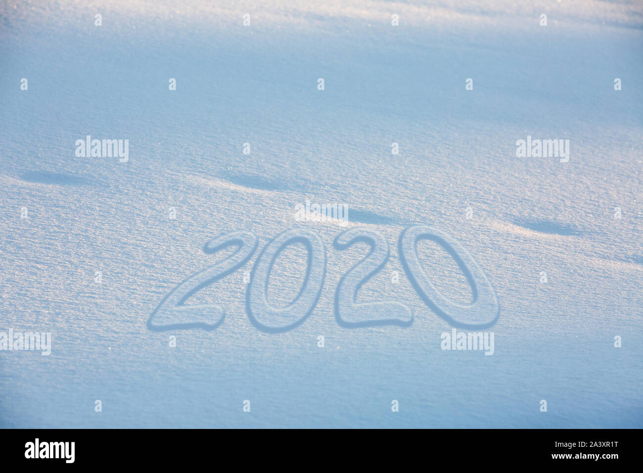 The numbers 2020 are written on snow on a smooth snowy surface. Tender ...