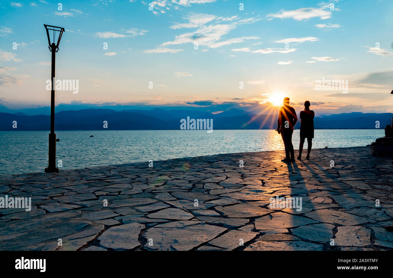 Silhouettes of couple caught by setting sun 11standing on craxy paving ...