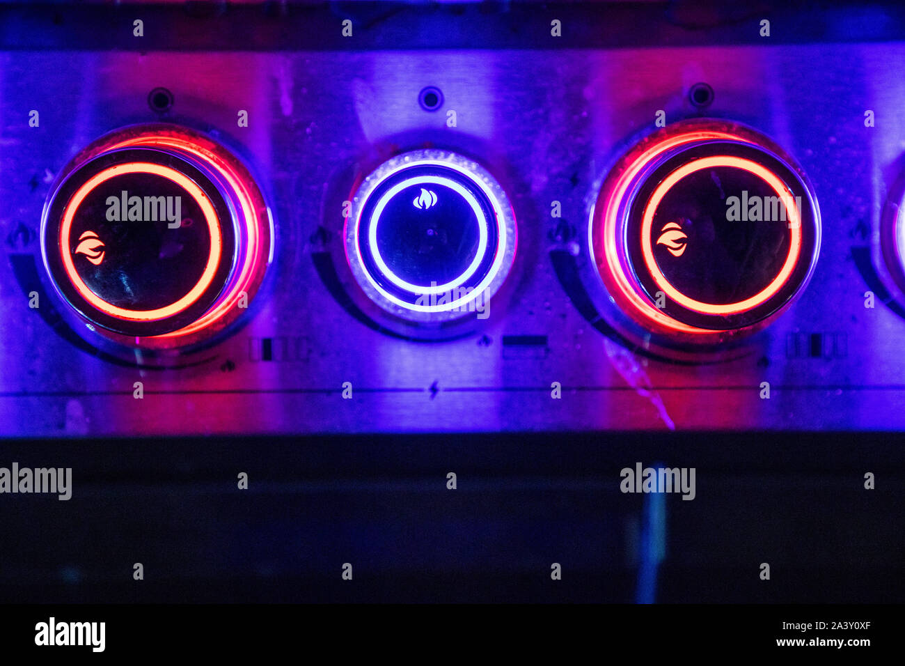 Controls of a gas grill, illuminated, red light up the burners, which ...