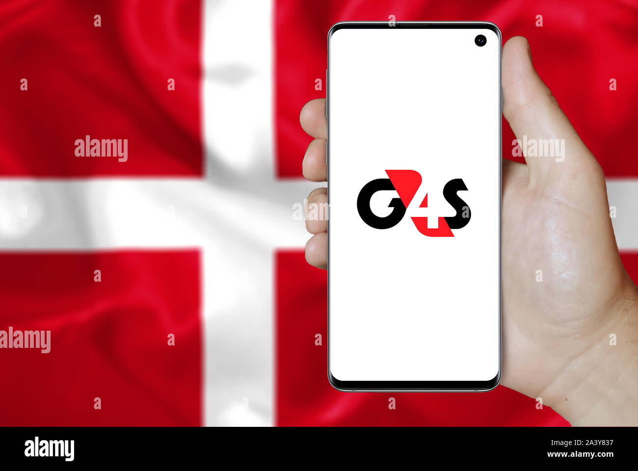 A man holds a phone displaying the logo of company G4S plc listed on ...