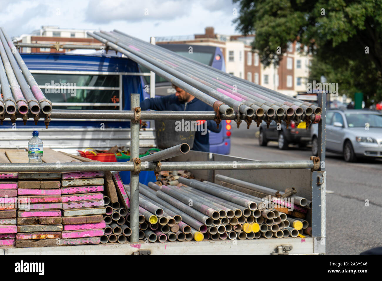scaffolding poles on a van with a scaffolder in the background working ...