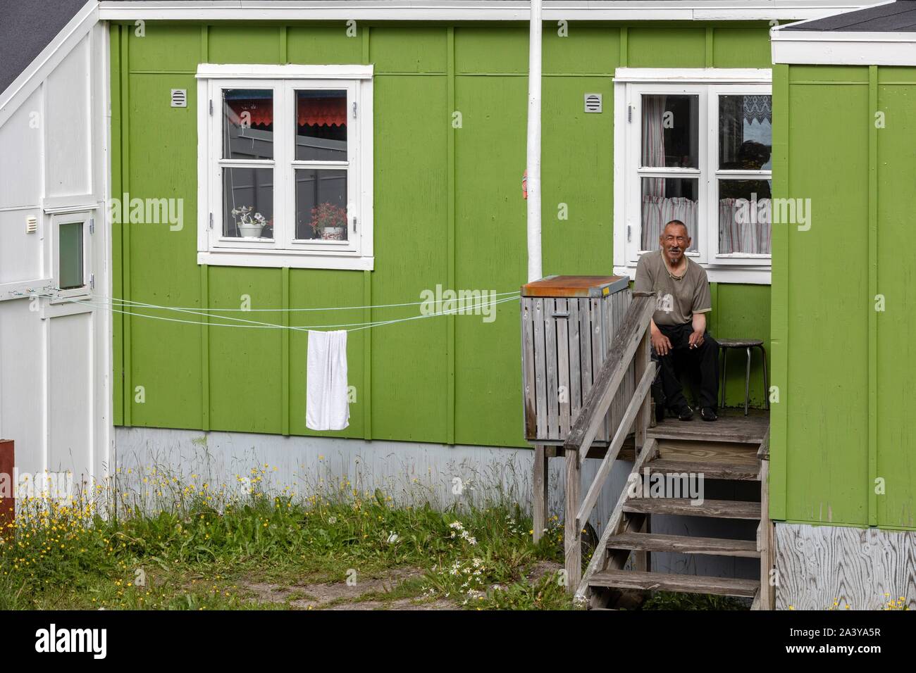 RESIDENT SMOKING A CIGARETTE IN FRONT OF HIS TRADITIONAL GREEN WOODEN ...