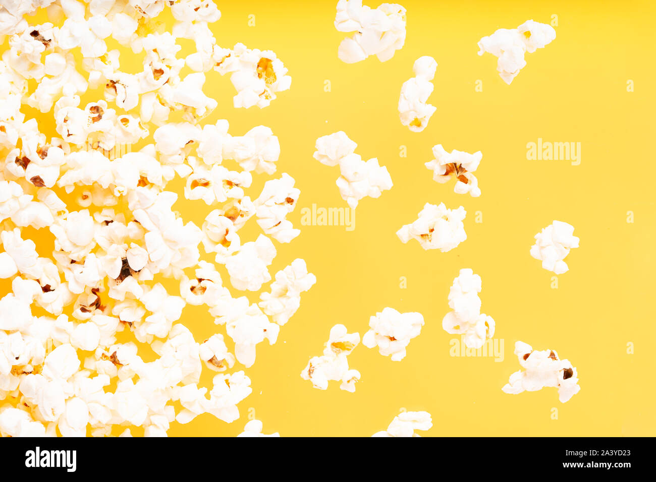 Scattered popcorn over yellow background Stock Photo - Alamy