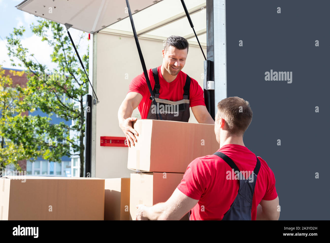 Smiling Young Male Mover Unloading In A Moving Van And Passing A ...