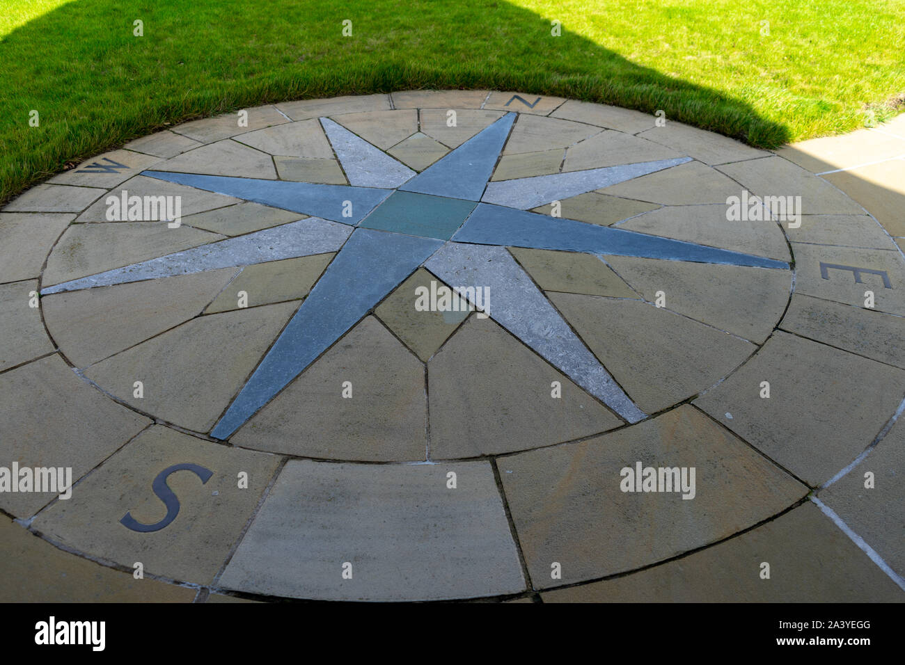A compass on the ground made in paving stones showing north south east ...