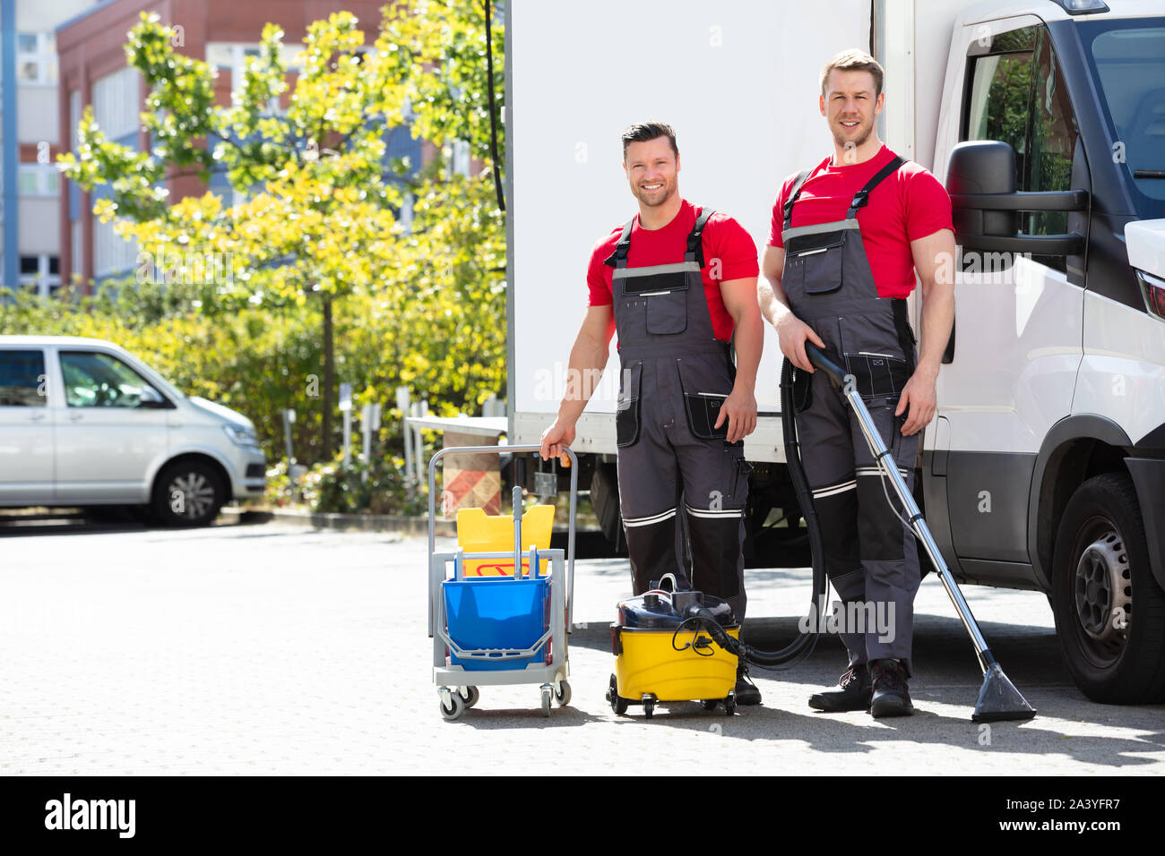 Two Young Male Janitors With Cleaning Equipment Standing Against Truck ...