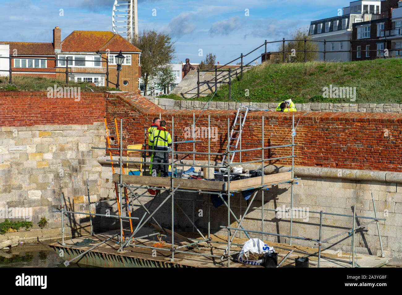 Bricklayers working on repairing a brick wall standing on scaffolding ...