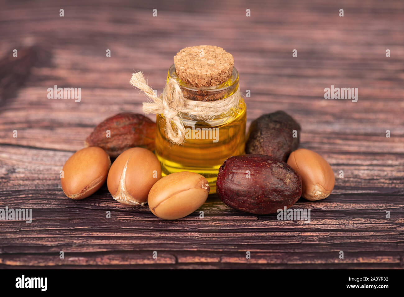 Argan oil, on wooden background. Argan nuts and seeds, for cosmetic and ...