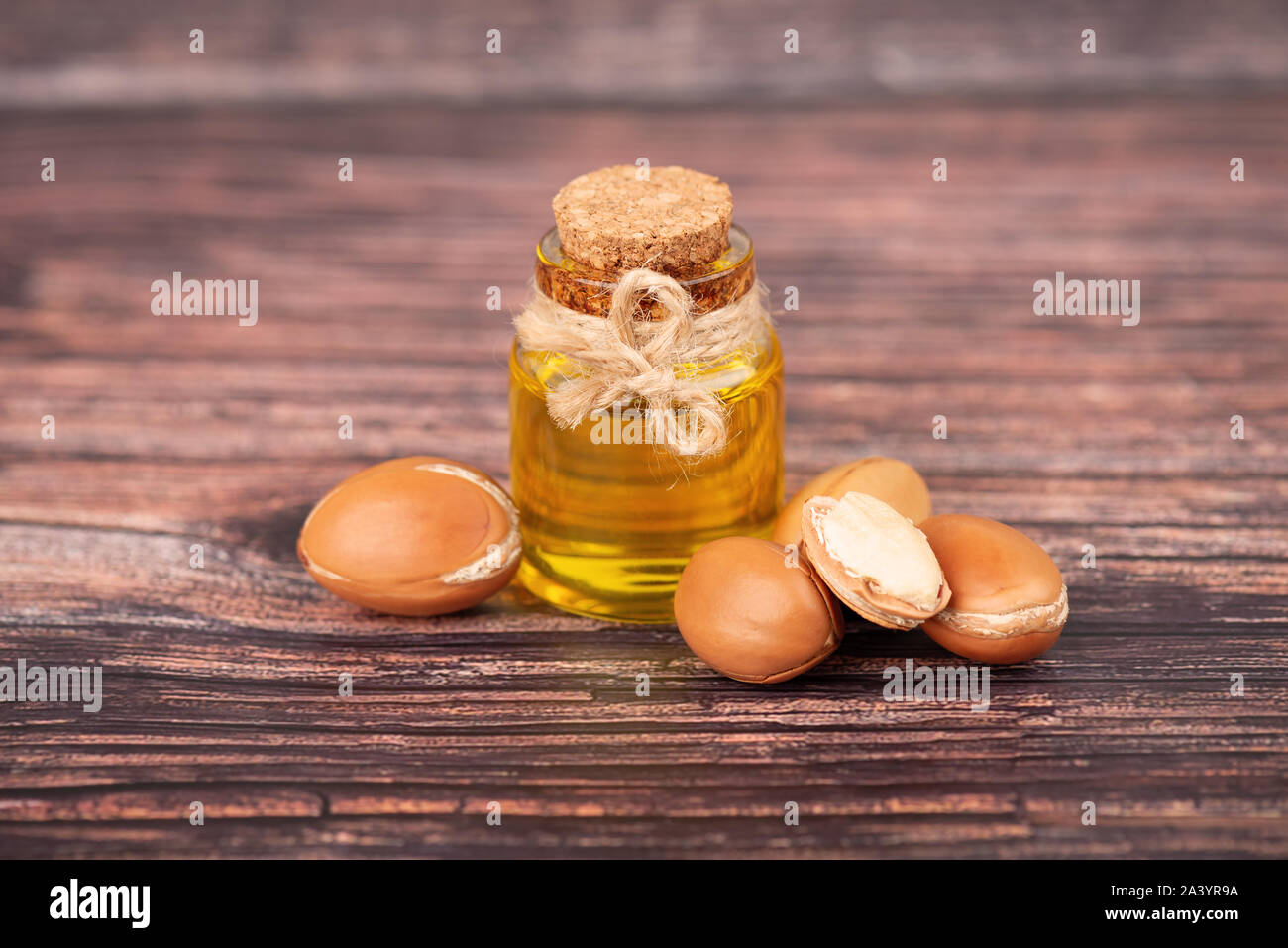 Argan oil, on wooden background. Argan nuts and seeds, for cosmetic and ...