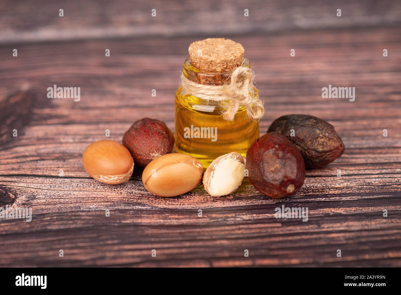 Argan oil, on wooden background. Argan nuts and seeds, for cosmetic and ...