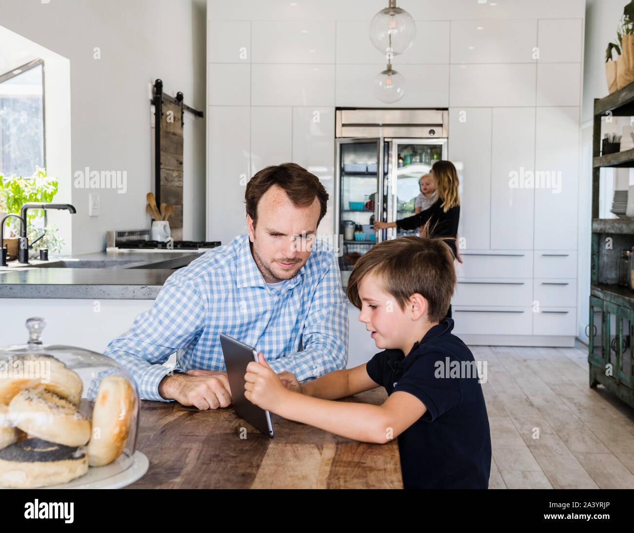 Father and son using digital tablet at dining table Stock Photo - Alamy