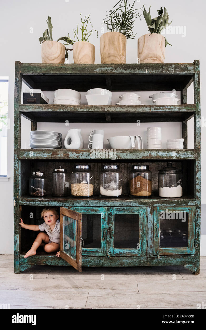 Boy hiding in cupboard in kitchen Stock Photo - Alamy