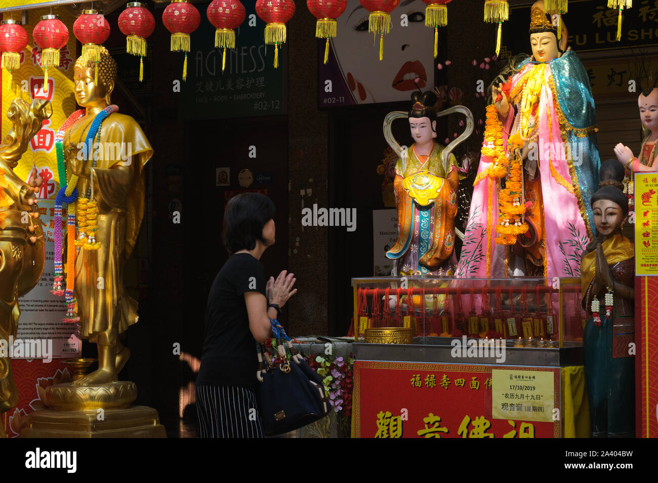 A woman prays at a Taoist prayer shrine in Waterloo Street, Bugis ...