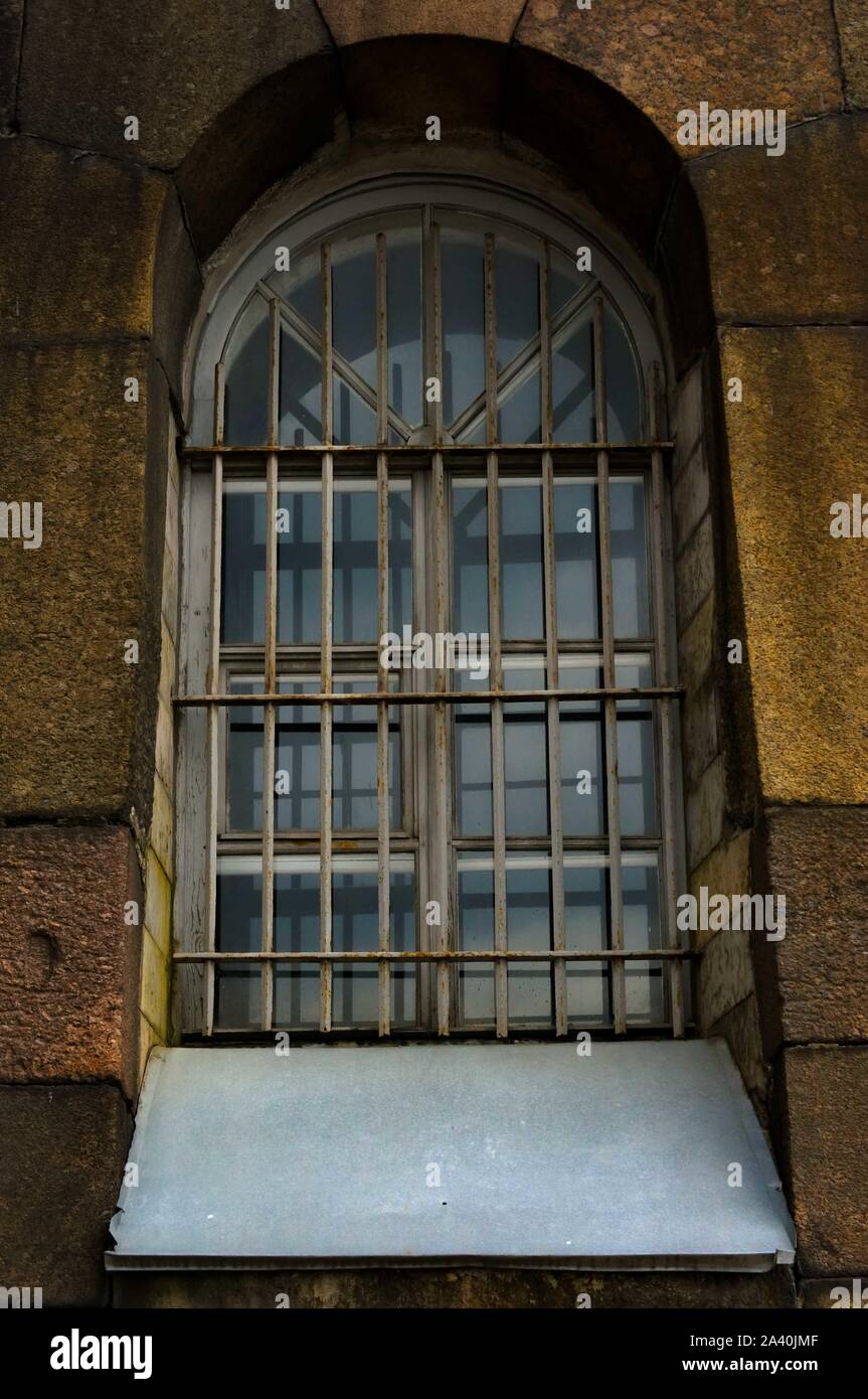 Gloomy window with grating on gray stone wall of historical building ...