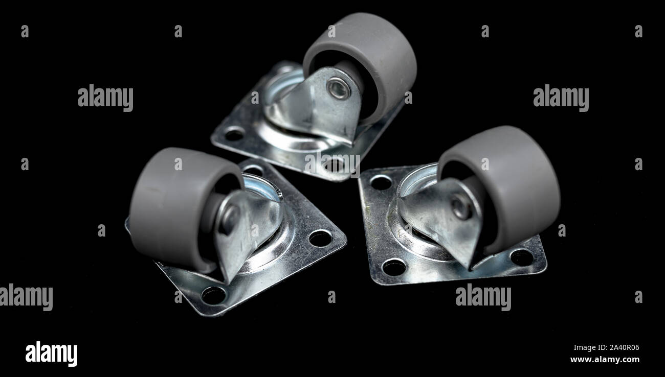 Three metal and rubber wheels to install in furniture Stock Photo - Alamy