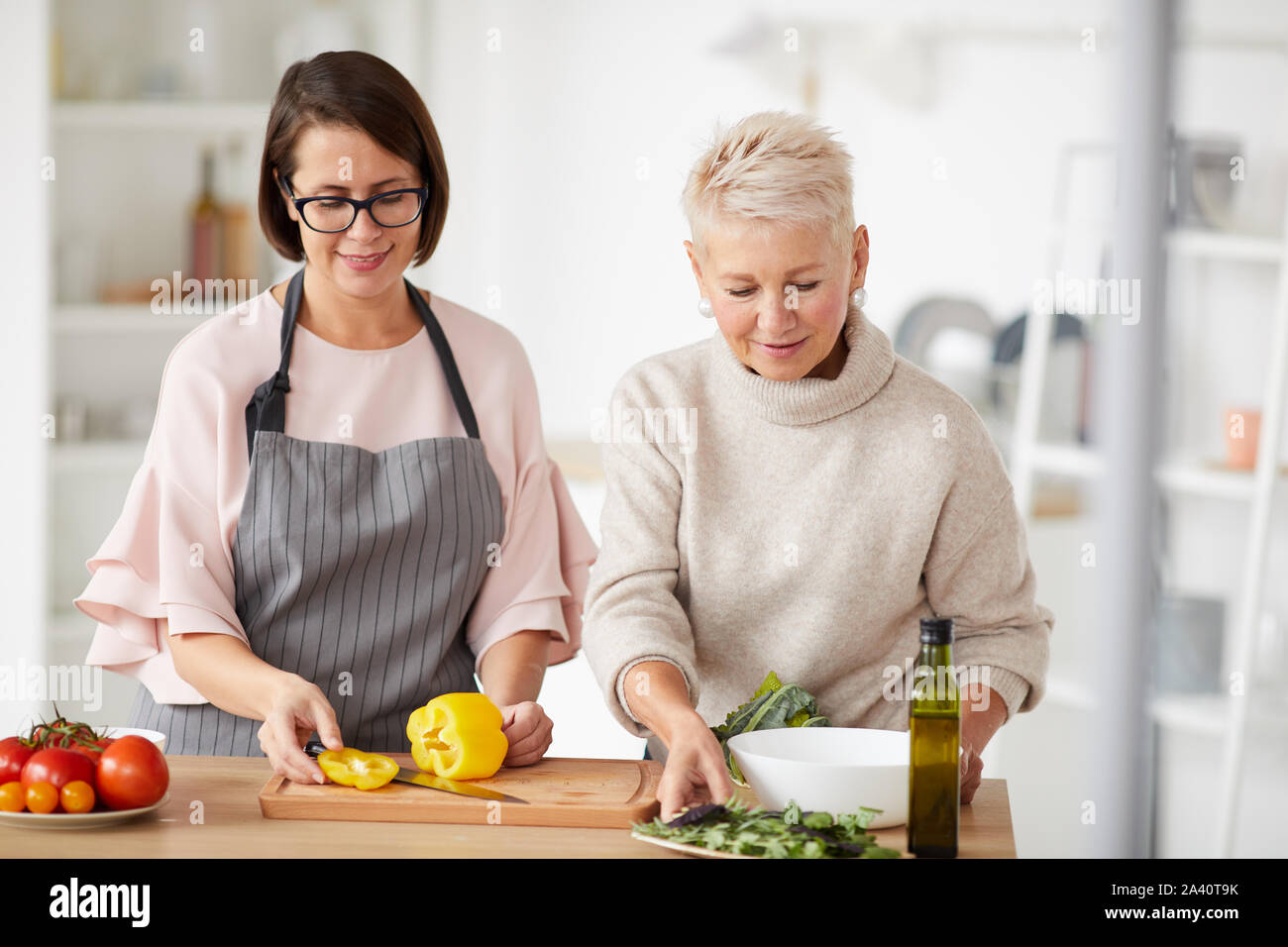 Two women standing together in the kitchen and preparing dinner for ...