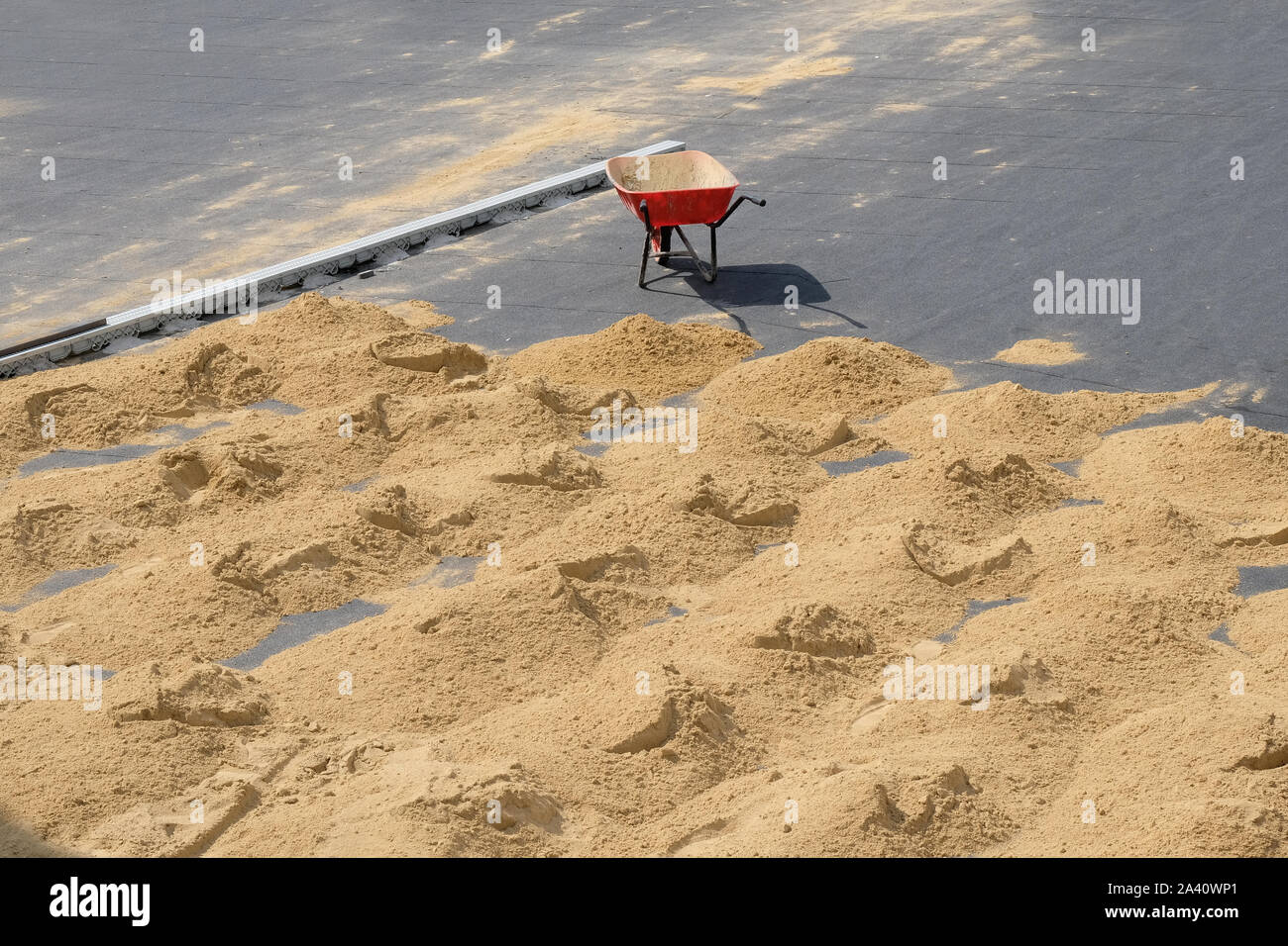 Red wheelbarrow with one wheel on the pavement and many small slides of ...