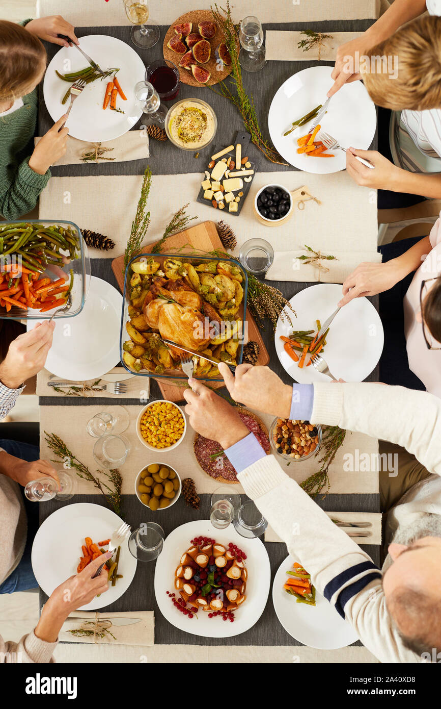 High angle view of family sitting at dining table and eating roast ...