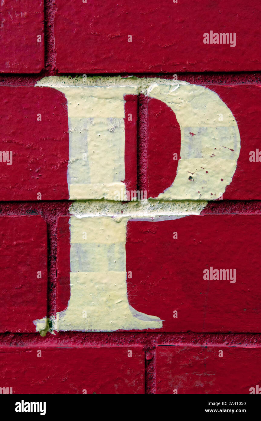A Close Up Of A Cream Coloured Letter P Painted On A Red Painted Brick ...