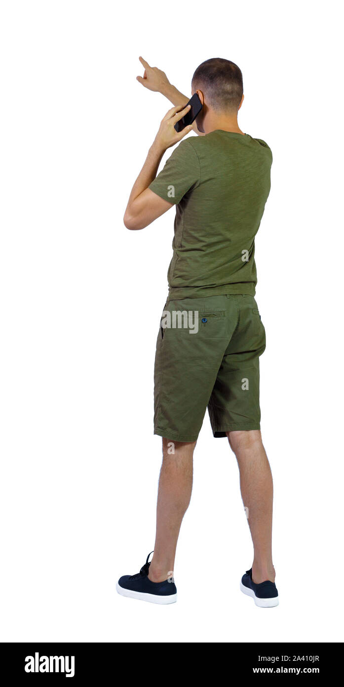 Back view of pointing man in shorts who is looking into the smartphone ...