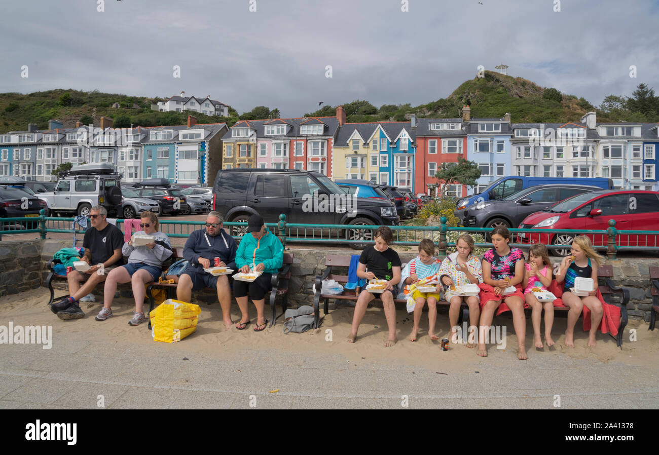 People eating fish and chips by the beach at Aberdovey (Aberdyfi) in ...