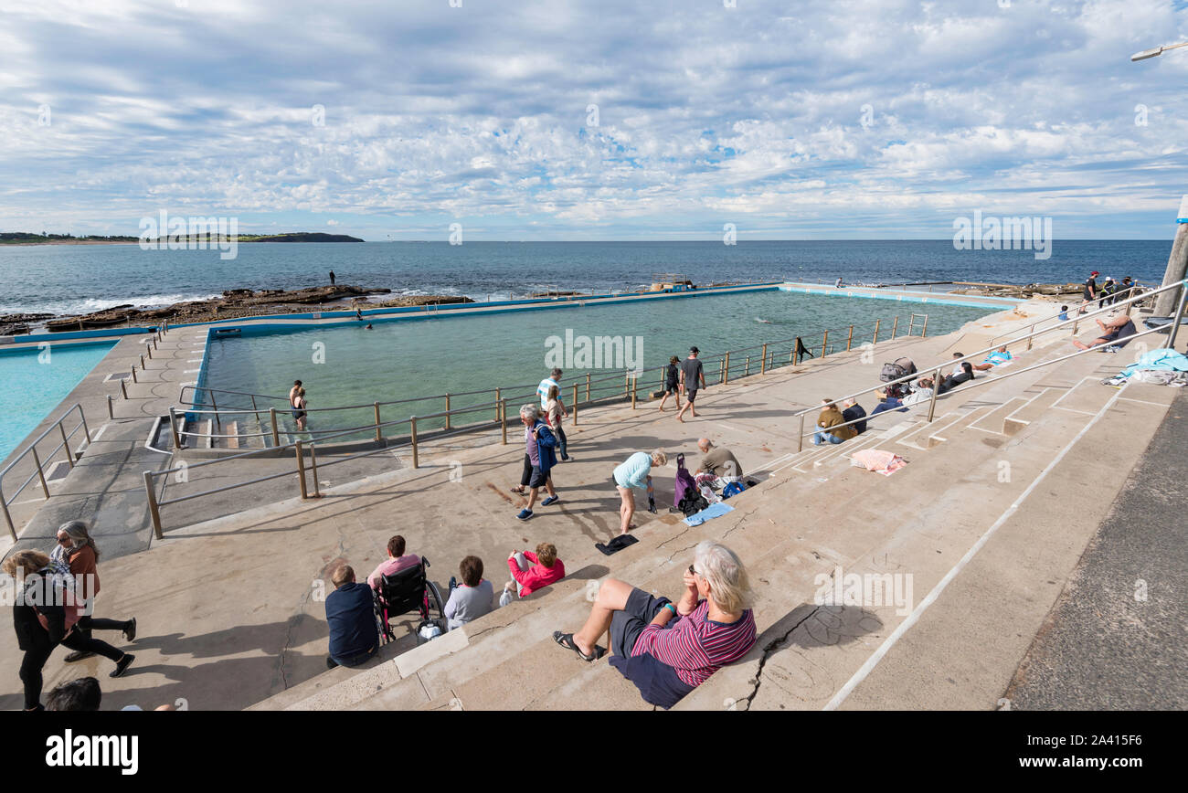 On a warm June day people soak up the sun, walk past and swim in the ...