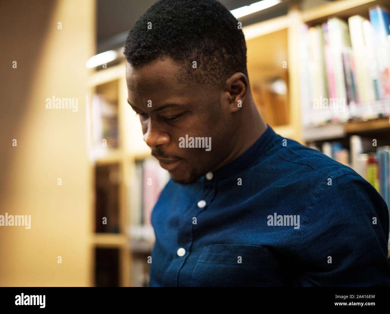 Young black man choosing book in public library Stock Photo - Alamy