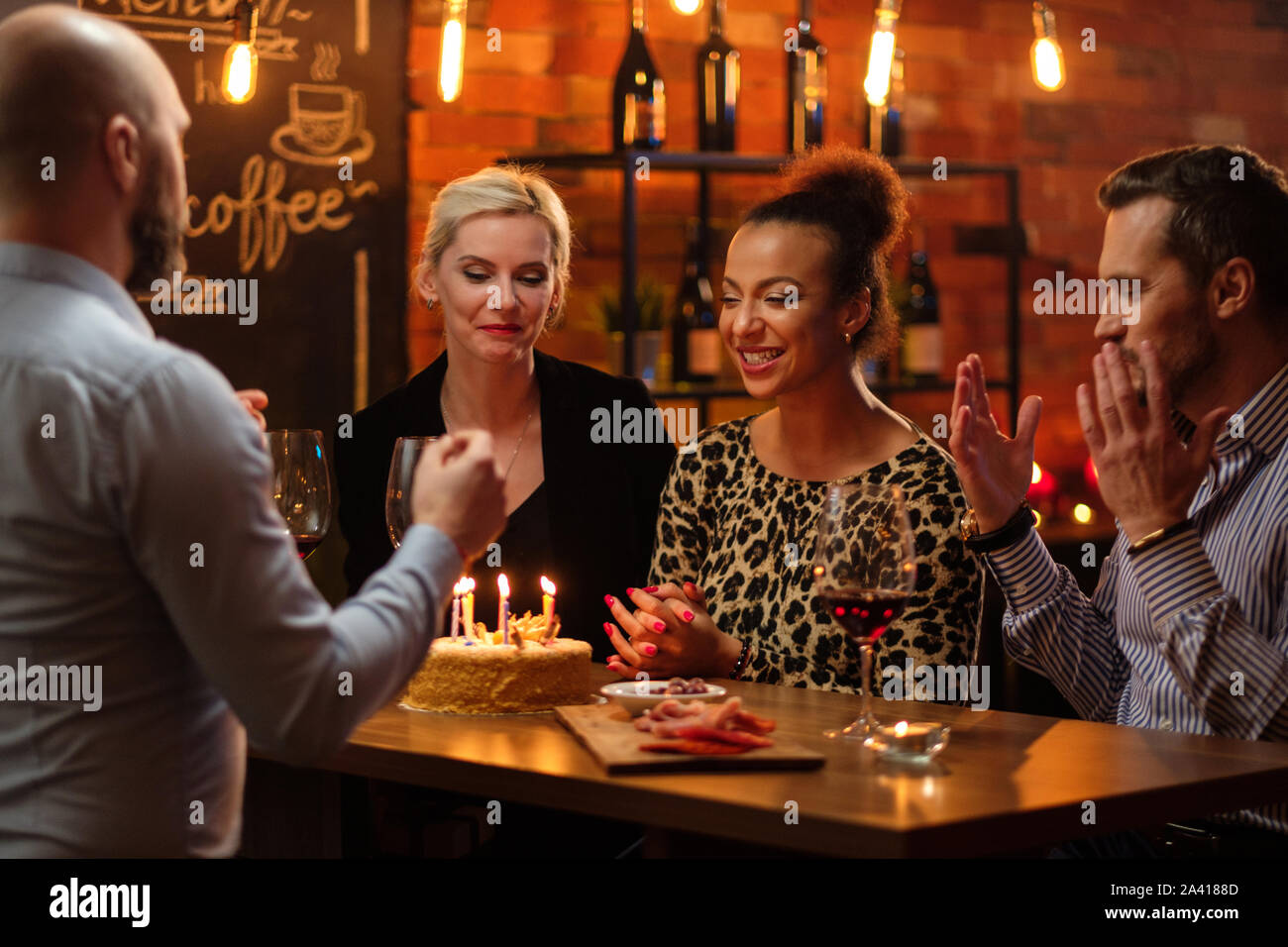 Group of friends celebrating birthday in a cafe behind bar counter ...
