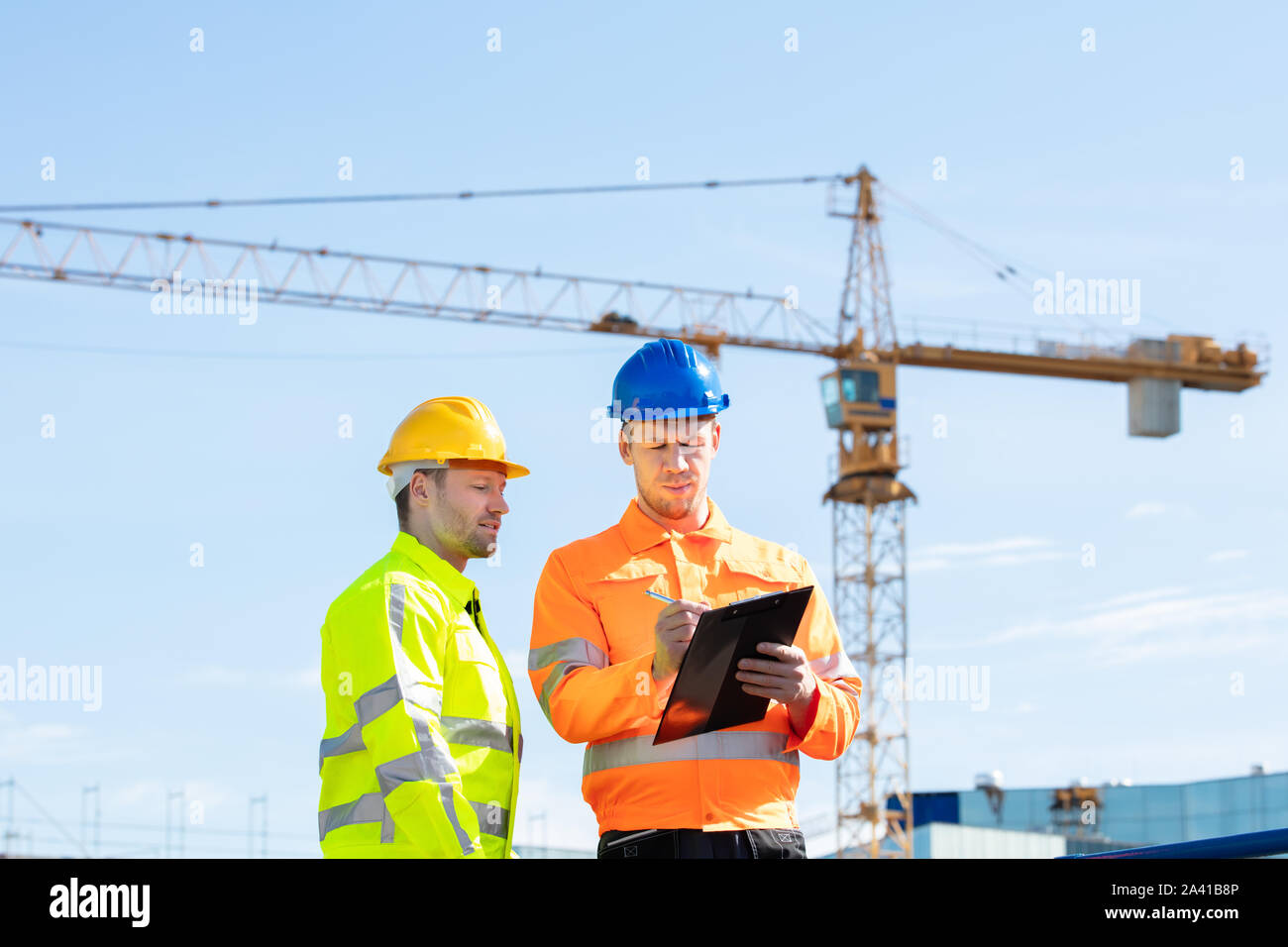 Male Architect Giving Instructions To His Foreman On Clipboard Working ...